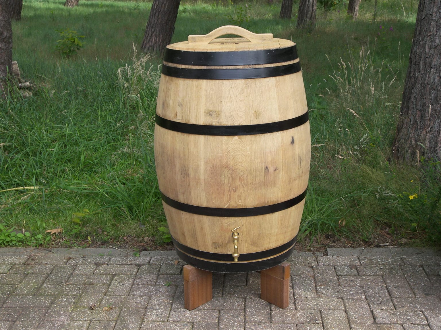 Regenton met zwarte banden en messing kraan en zwarte houten verhoger ...