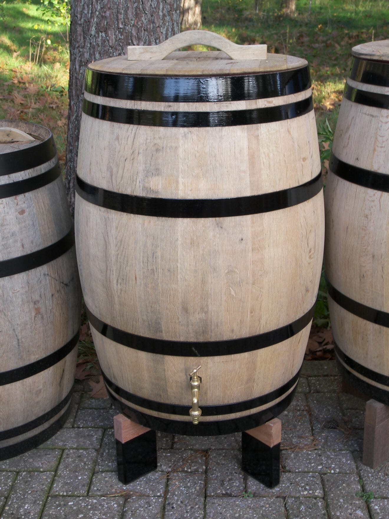 Regenton met zwarte banden en messing kraan en hout/ijzeren verhoger ...